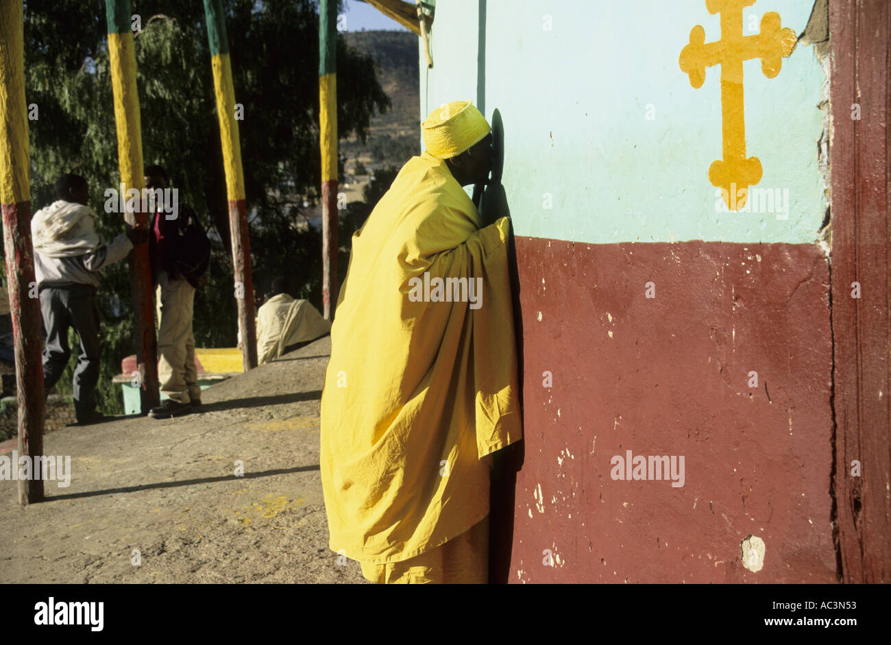 Yellow robed priest kissing the wall of the 19th century Adigrat ...