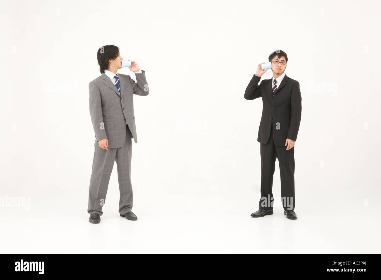 Two young businessmen talking with string and cups Stock Photo - Alamy