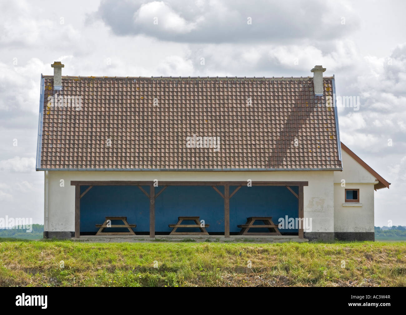 Open front white building with low roofline and steep roof and red ...