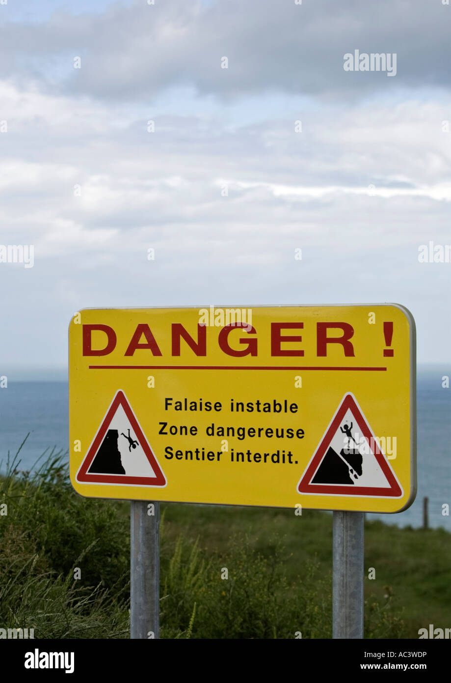 Bilingual french and english Yellow metal danger sign on cliff edge ...