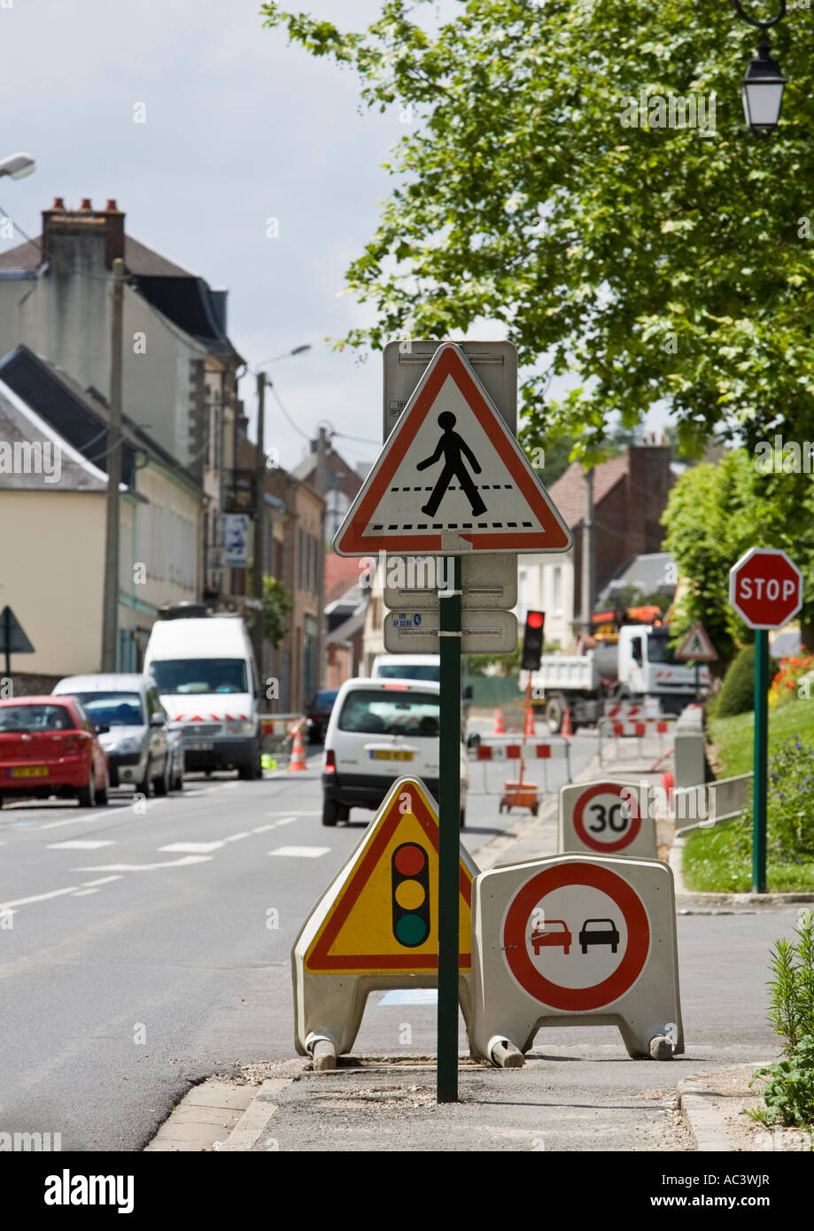 Fixed and temporary french road traffic signs on pavement with parked ...