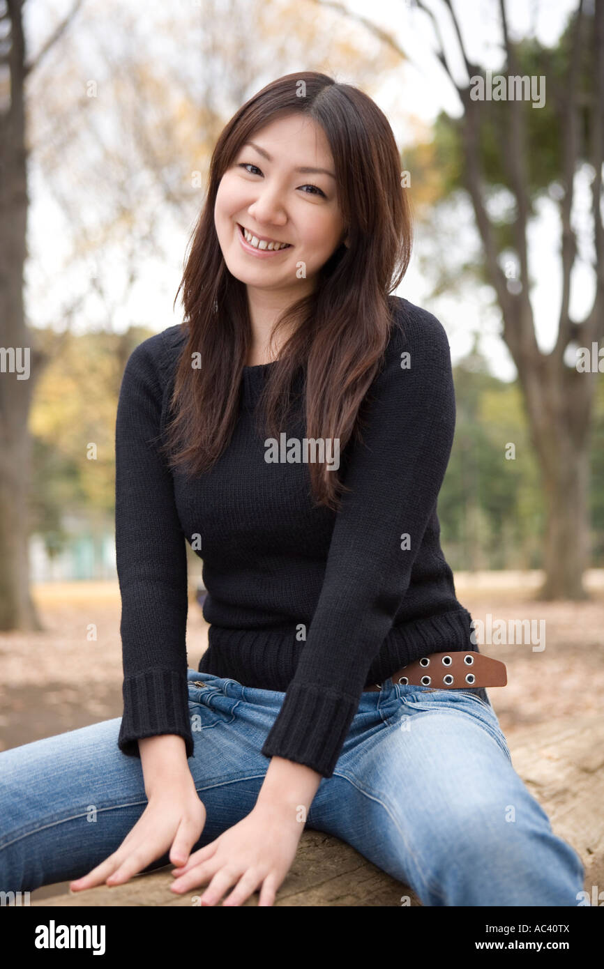 Young woman sitting on log Stock Photo - Alamy