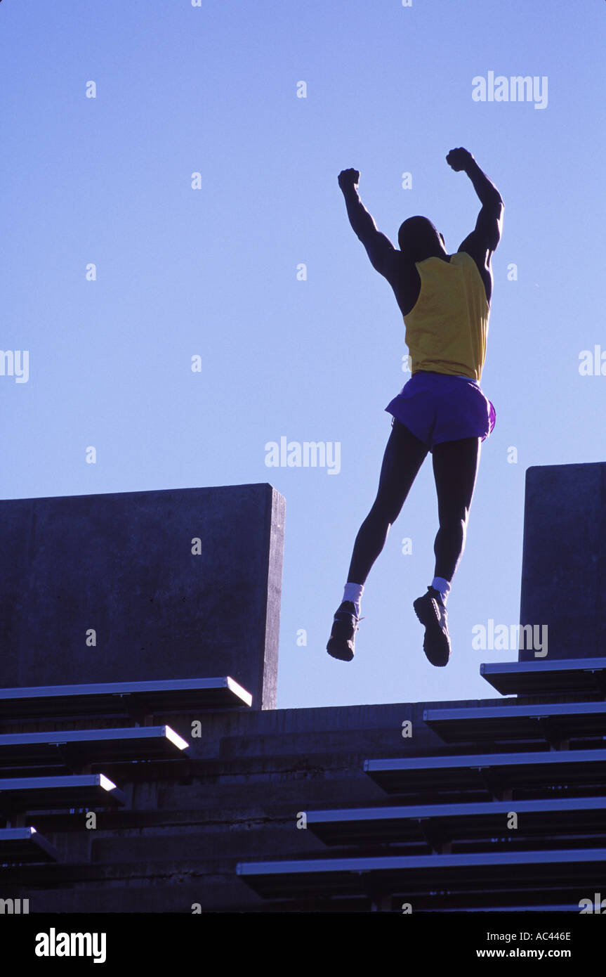 African American male athlete jumping in victory pose atop steps Stock ...