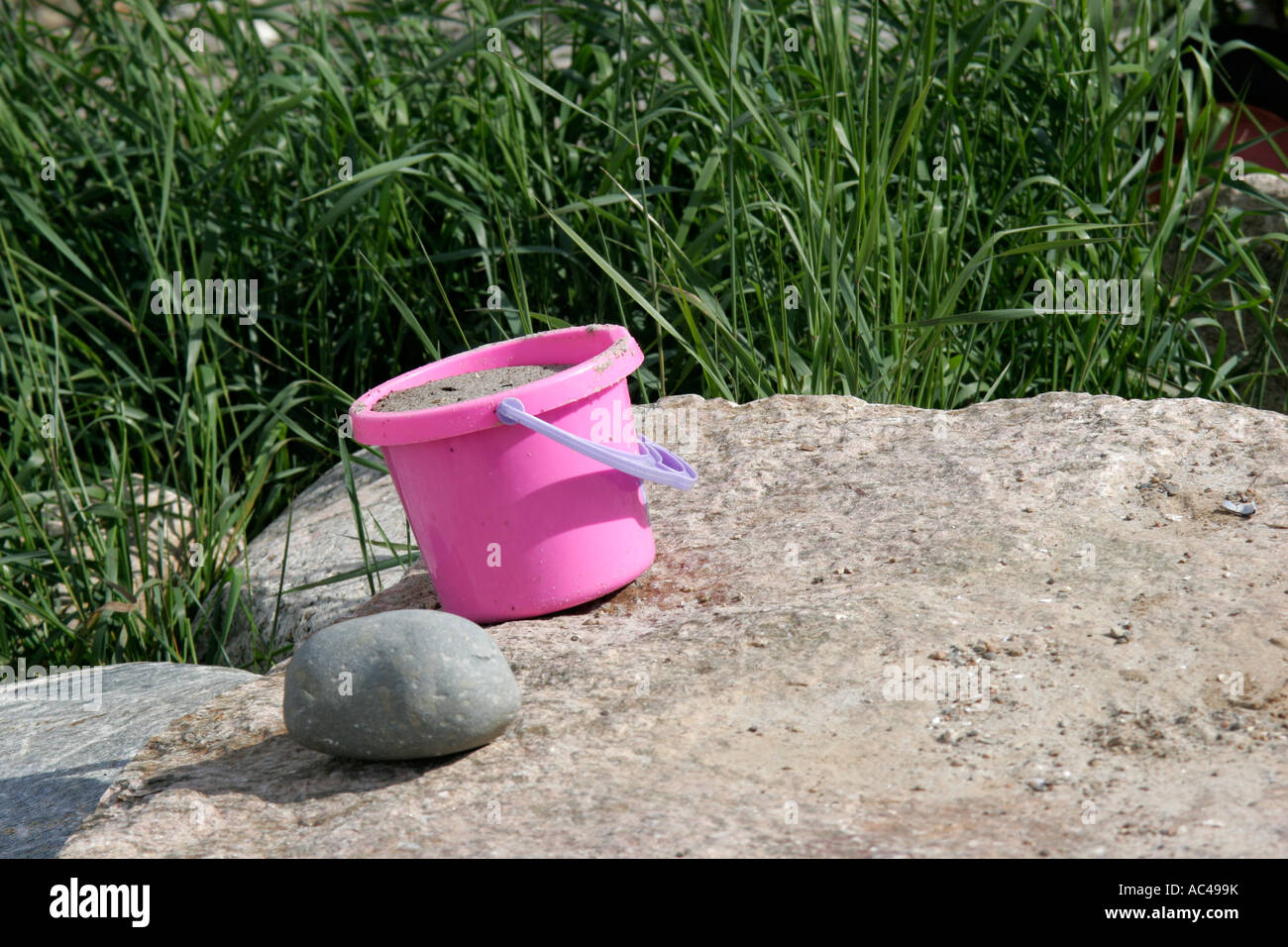 Pink bucket on a rock Stock Photo - Alamy
