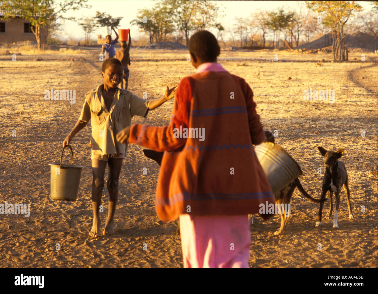 African boy greeting mother on his way back from collecting water in ...