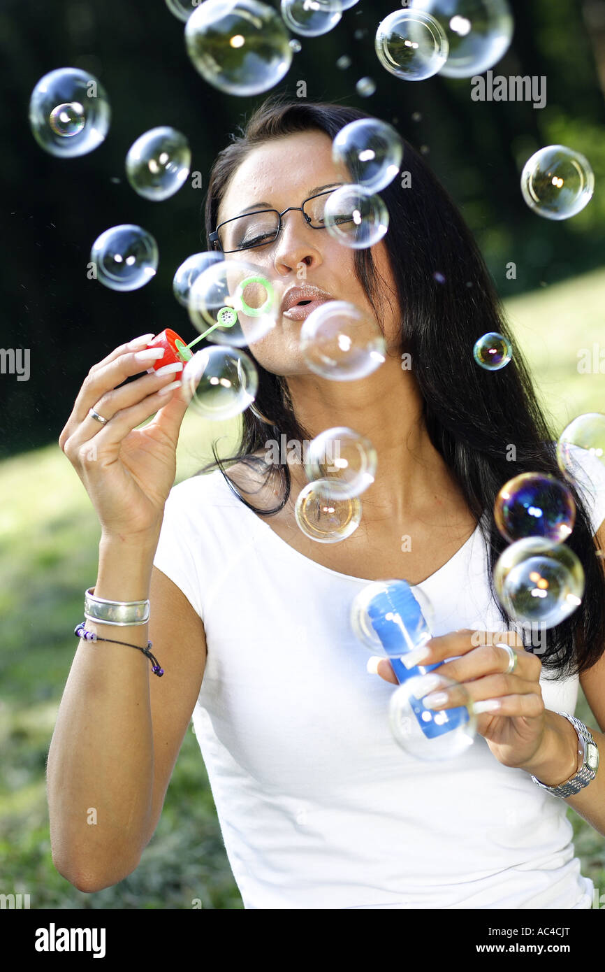 Junge Frau mit Brille blaest Seifenblasen young bespectacled woman ...