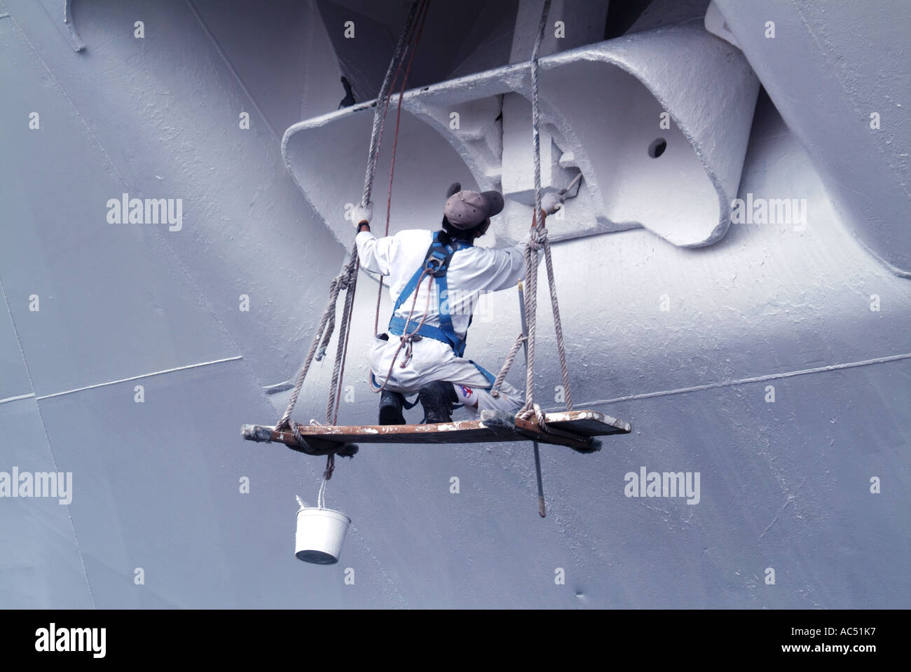Ajaccio port area man working on suspended narrow plank painting anchor ...