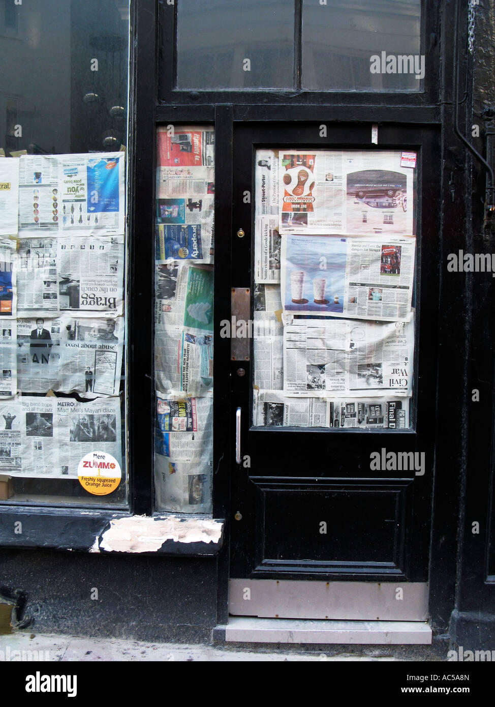 Old newspapers and peeling paint on the shabby shopfront of an empty ...