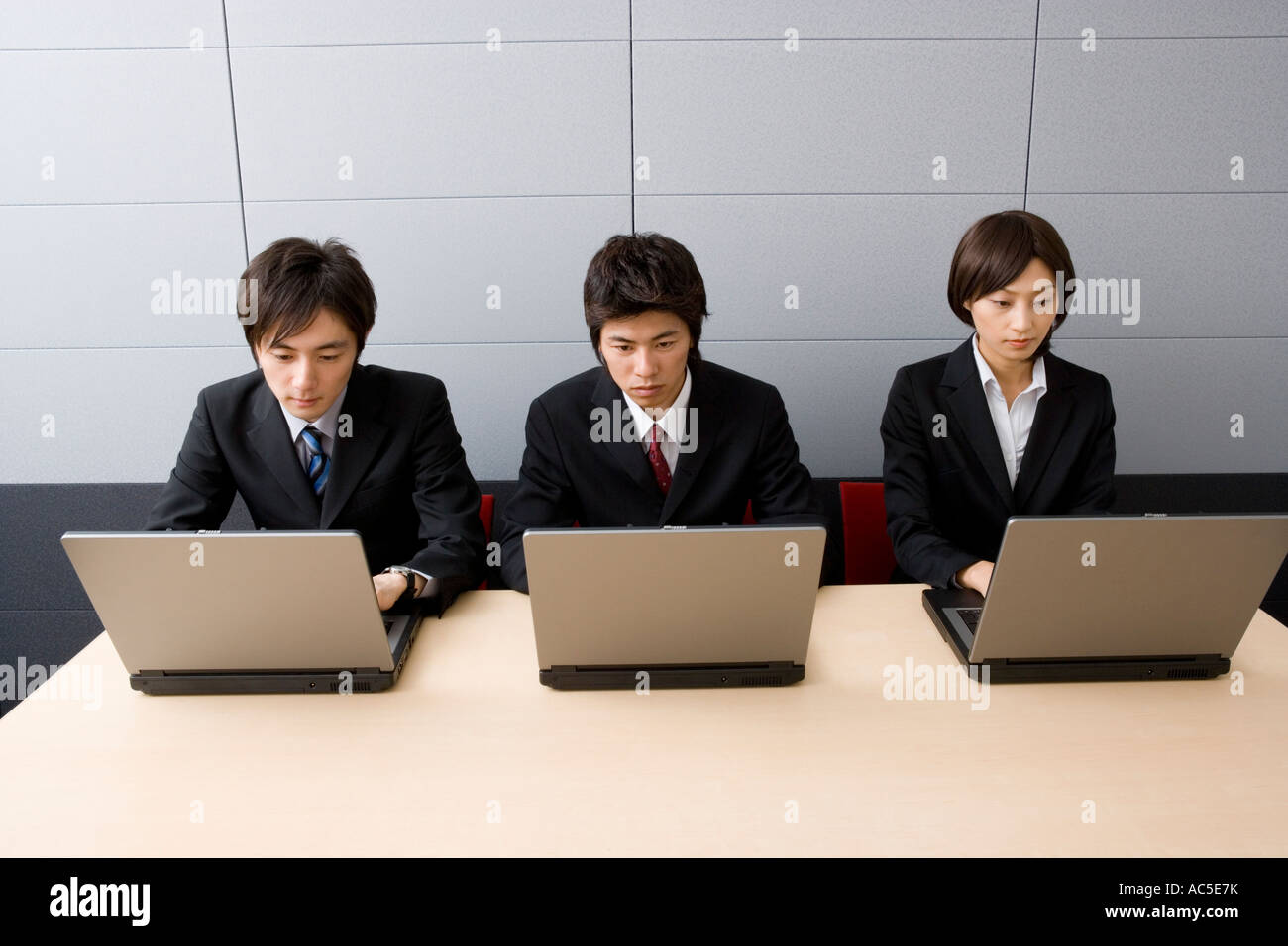 Three young business people using computers Stock Photo - Alamy