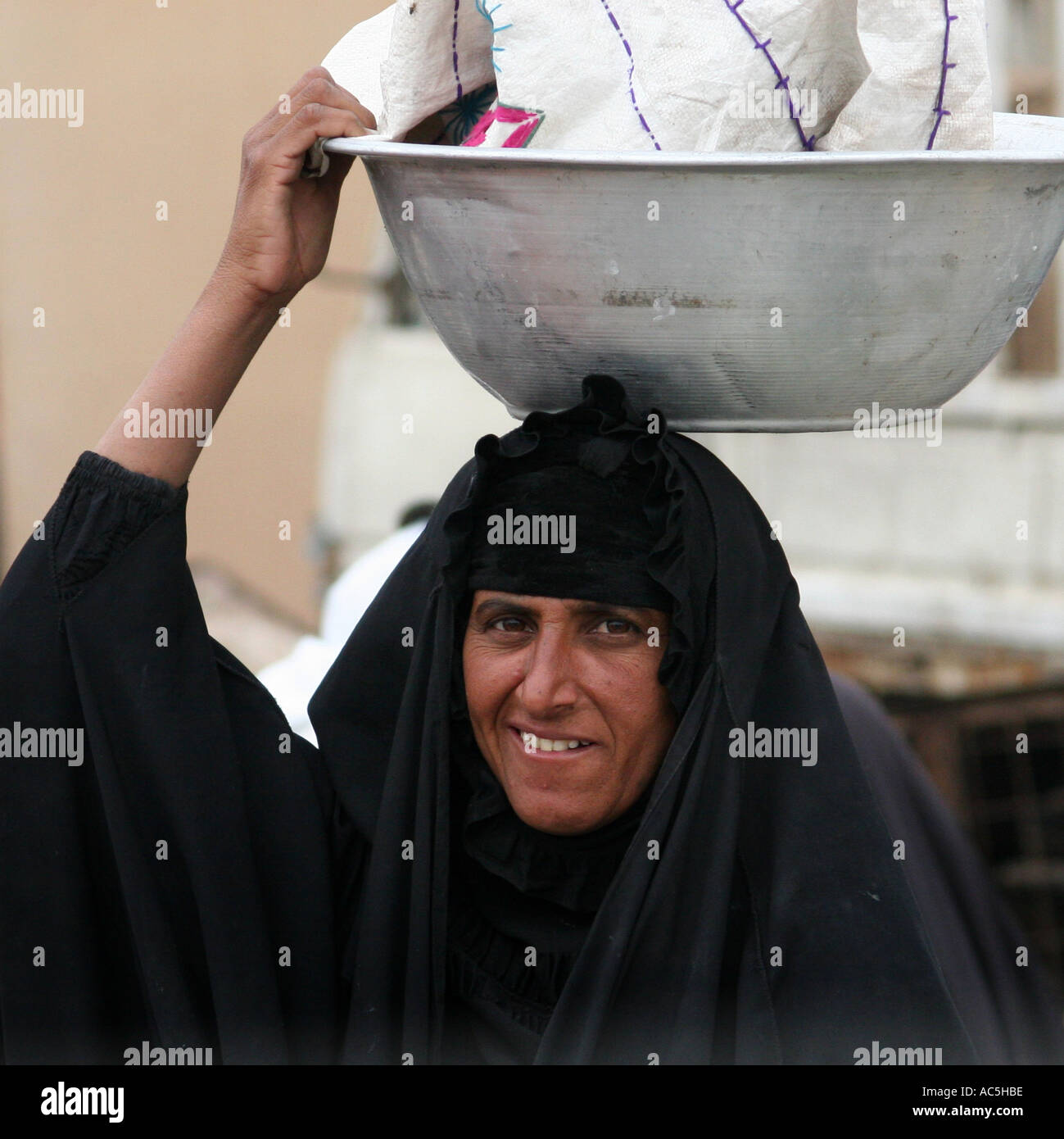 Iraq basra A woman wearing a frilly headscarf balances her basin on her ...