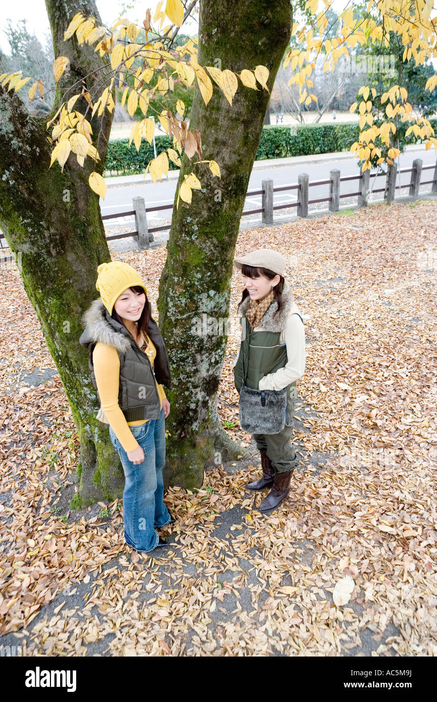 Two young women talking under tree Kamigamo Shrine Kyoto Prefecture ...