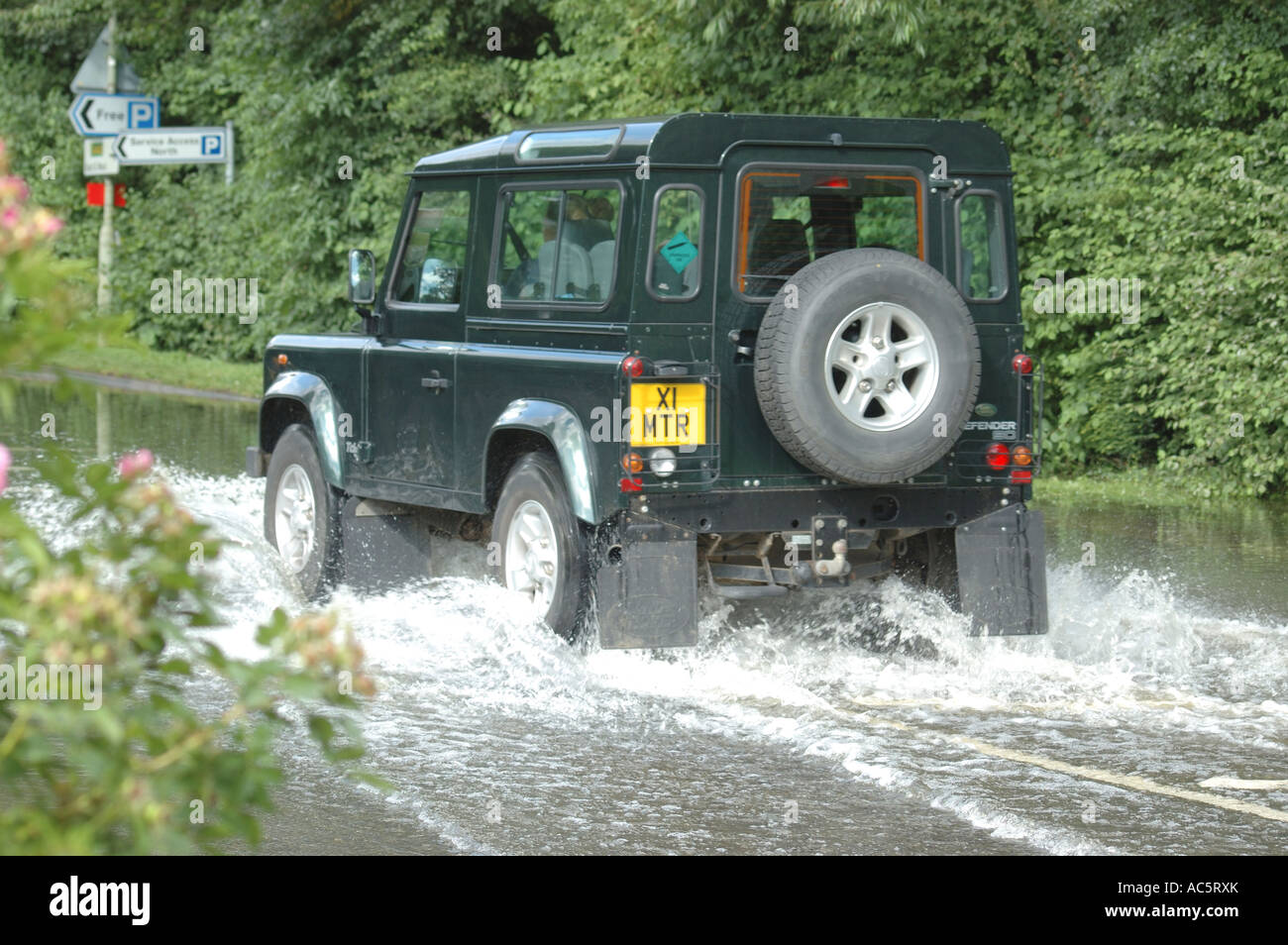 A motor car on a road driving through flood water Stock Photo - Alamy