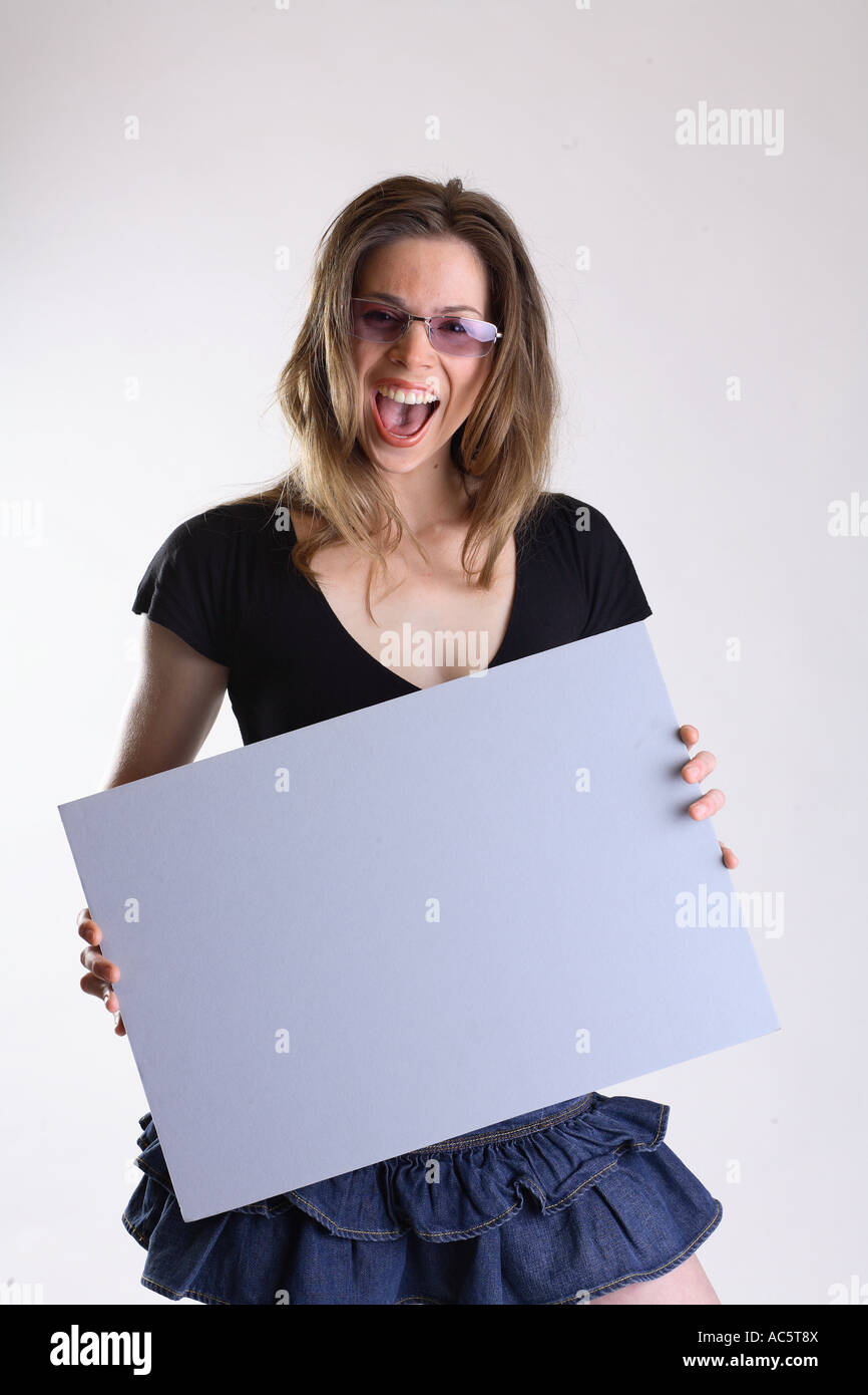 Junge Frau im Minirock praesentiert ein Schild young woman clad in a ...