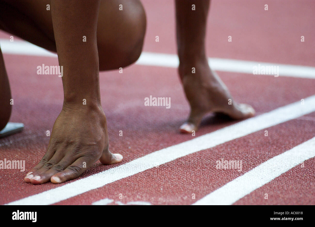 sprinter in starting position lines up his fingers with the starting ...