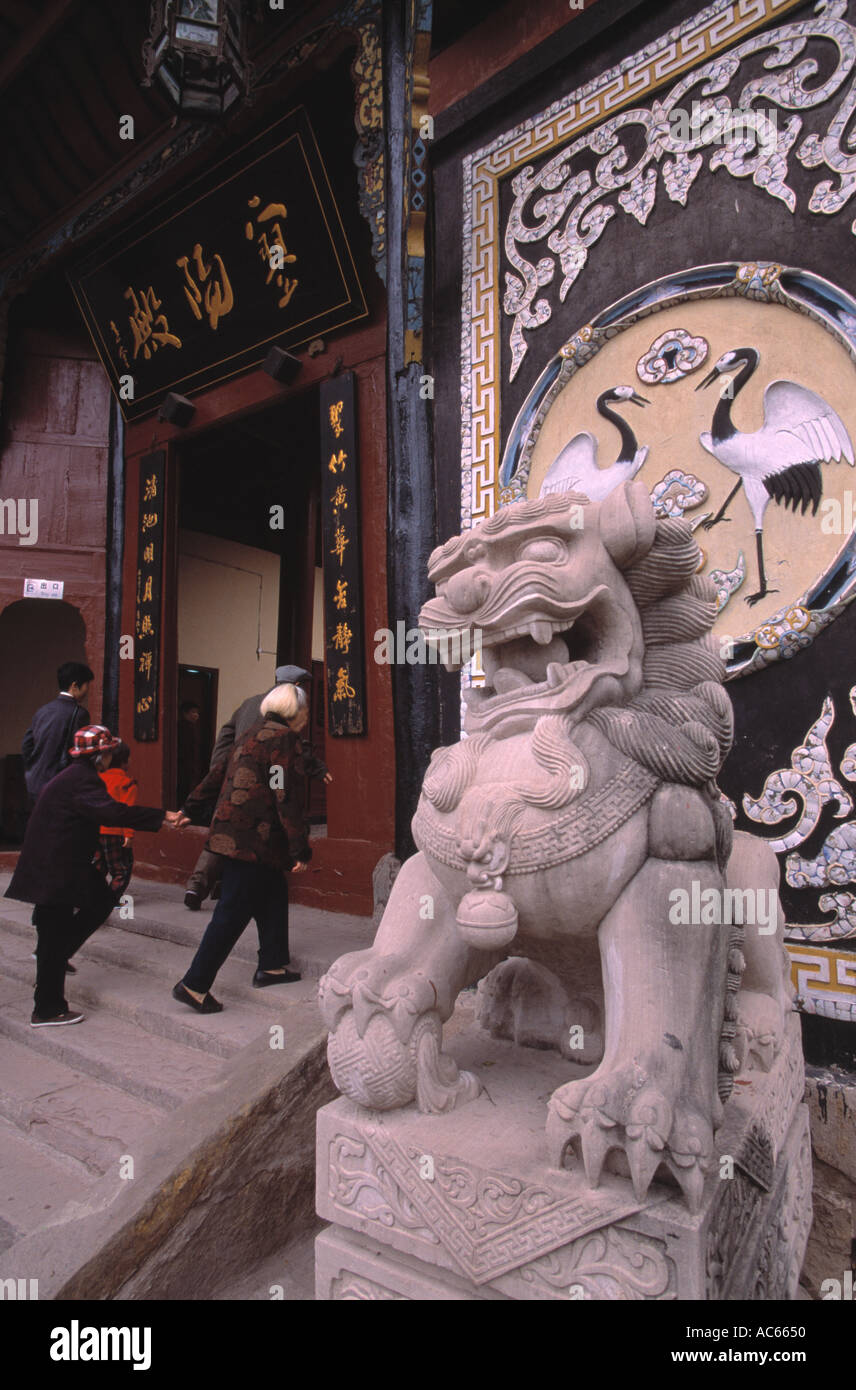 Tourists walk past mythical symbols while entering Ming Shan temple in ...