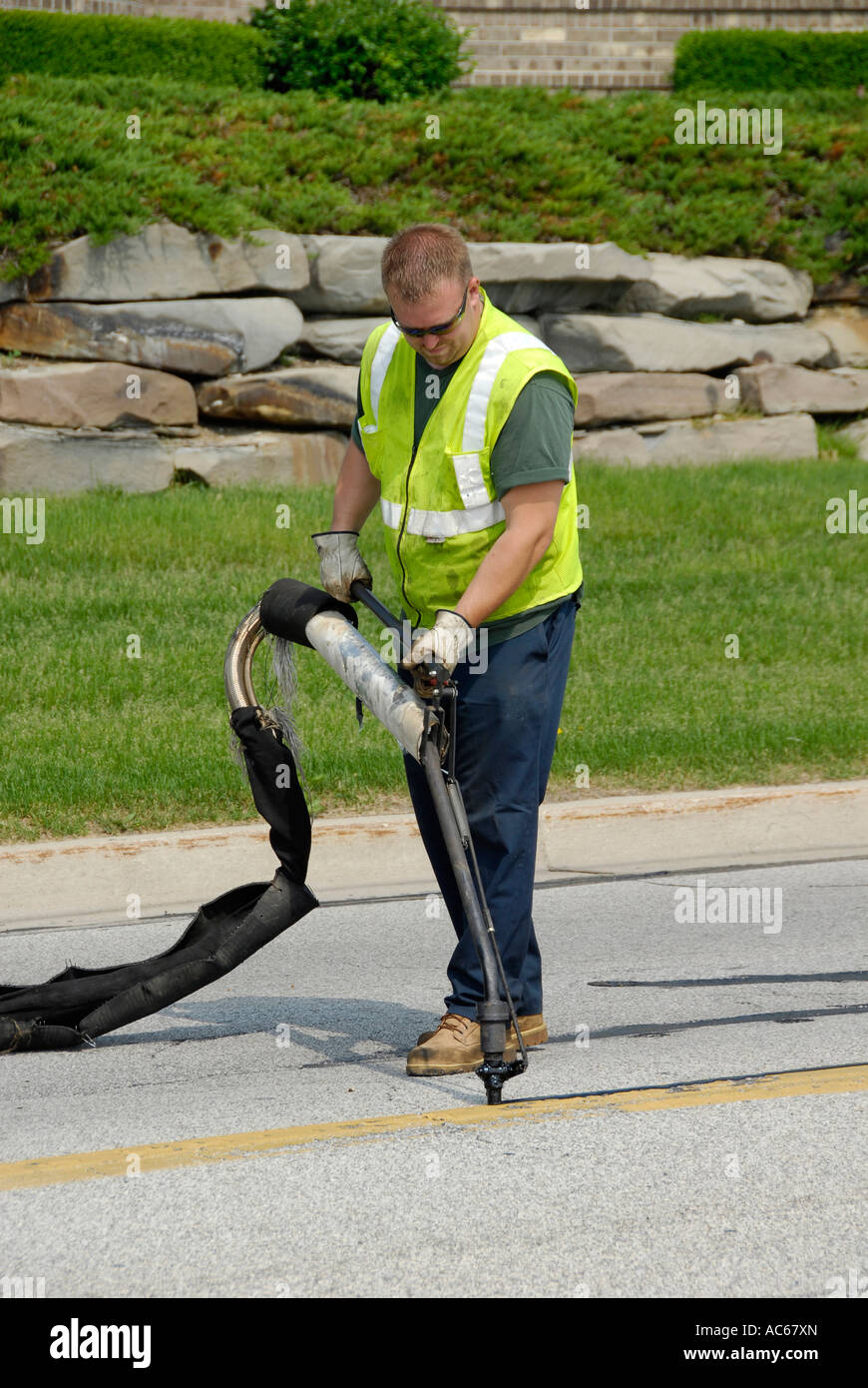 Road workers pour tar in the cracks of street pavement Stock Photo - Alamy