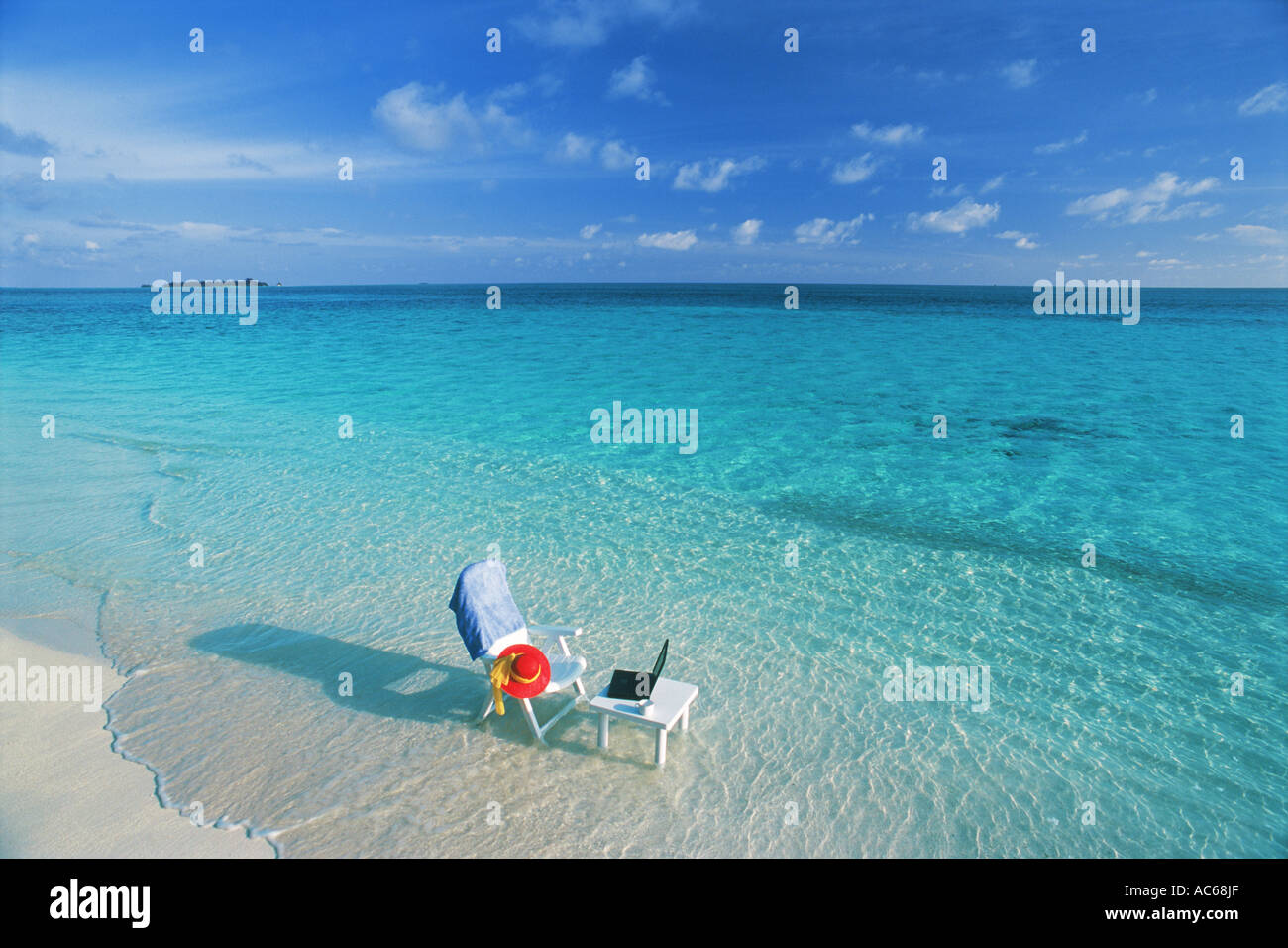 Chair and table with laptop and cellphone on beach in Maldives ...