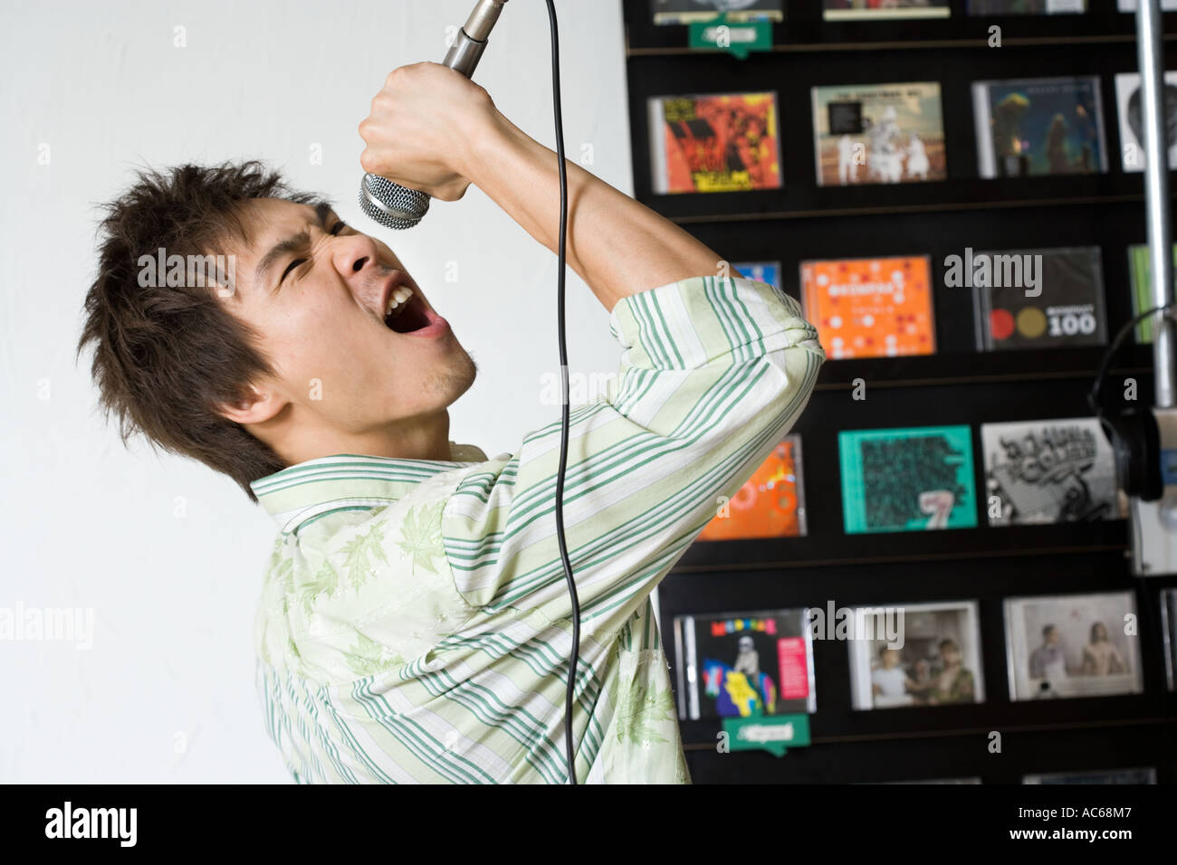 young man sings on microphone in record store Stock Photo - Alamy