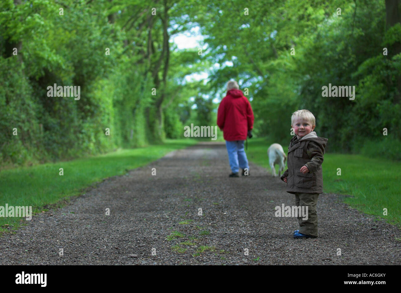 Child looking back on road with grandmother and dog in the background ...