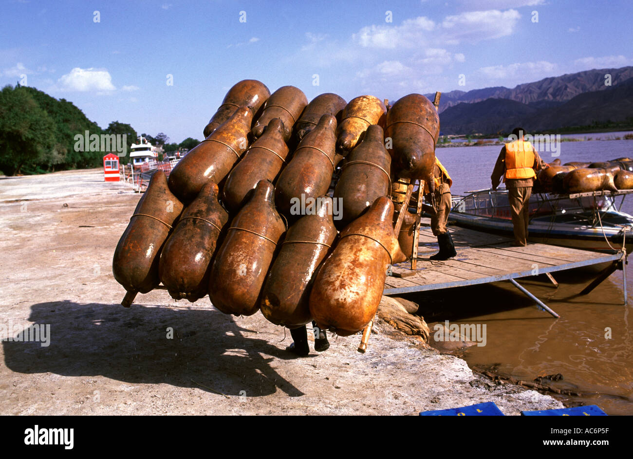 Man carrying a raft made from inflated sheepskin lashed to a wooden ...