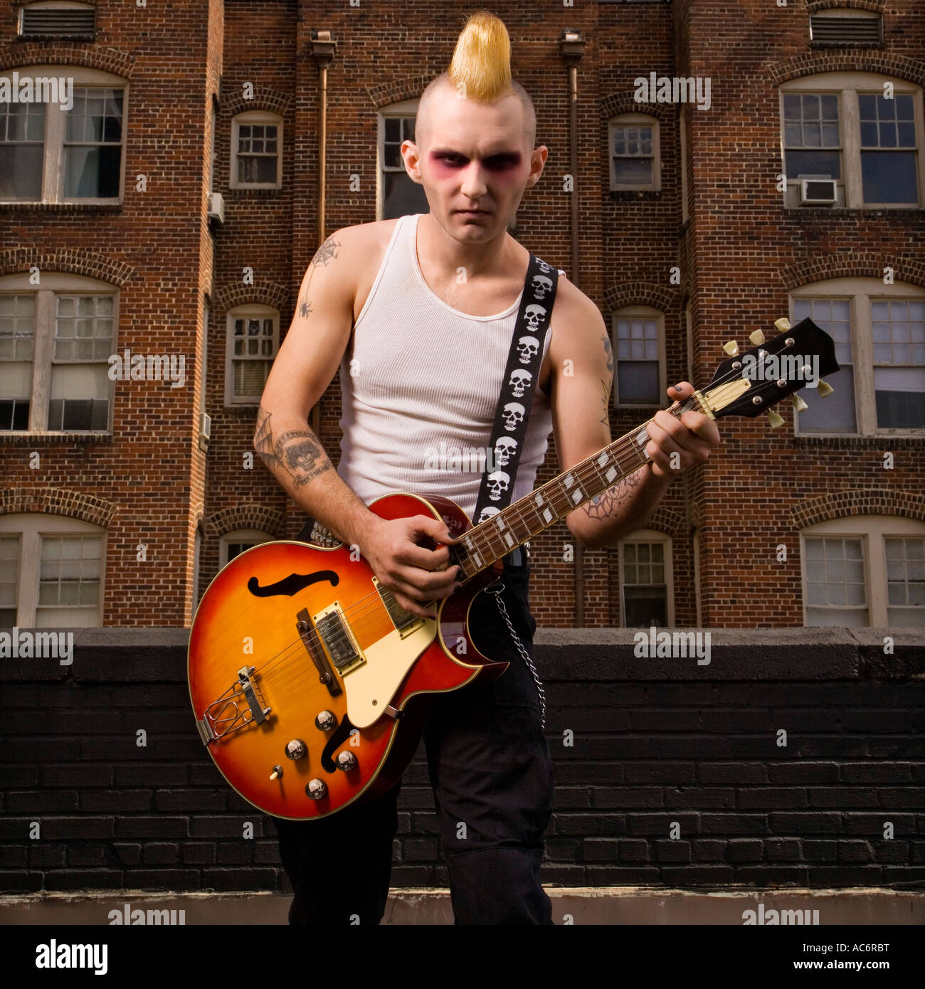 Portrait of a mid adult Caucasian male punk playing guitar with ...