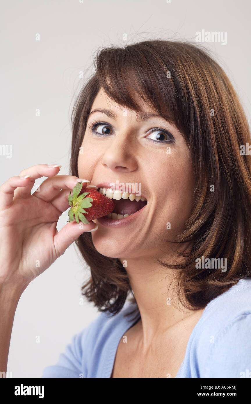 Eine junge Frau isst eine Erdbeere a woman eating a strawberry portrait ...