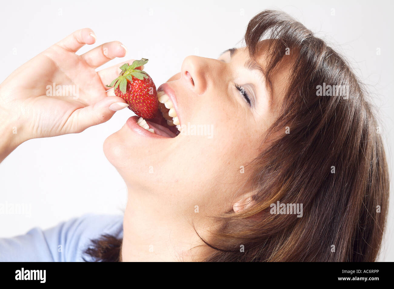Eine junge Frau isst eine Erdbeere a woman eating a strawberry portrait ...