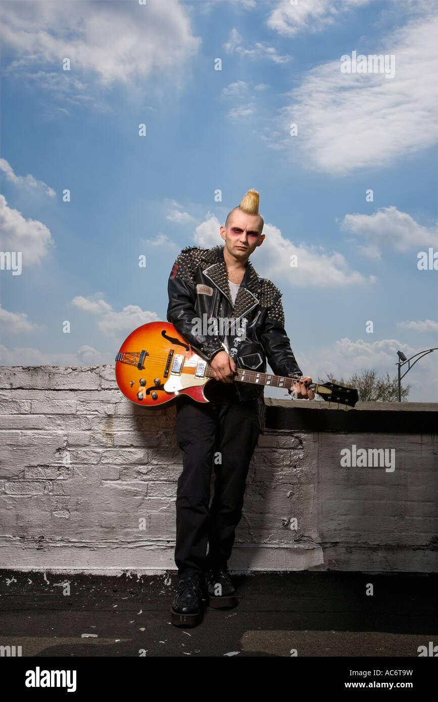 Portrait of mid adult Caucasian male punk holding guitar Stock Photo ...