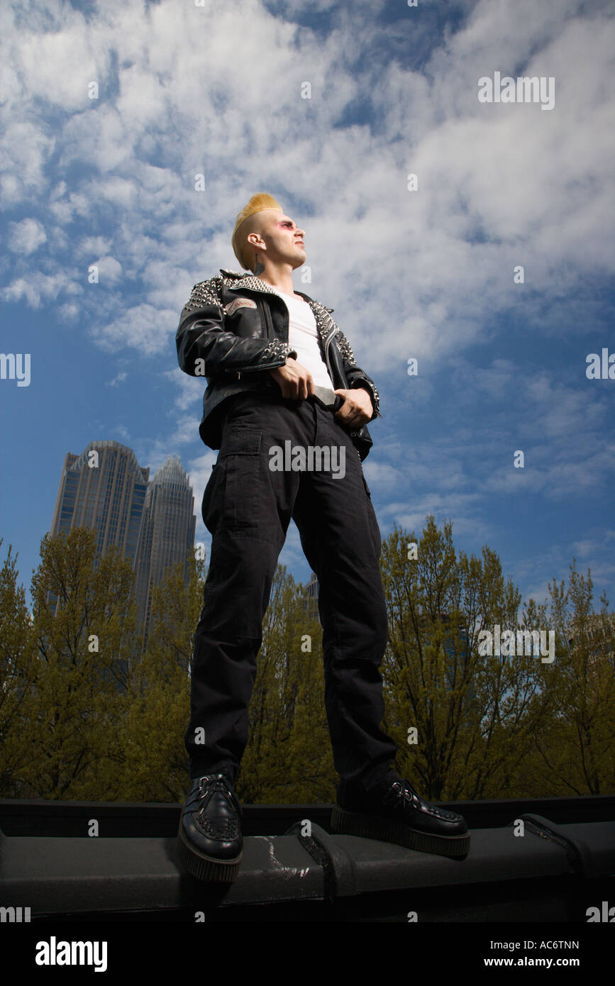 Portrait of mid adult Caucasian male punk standing on ledge with ...