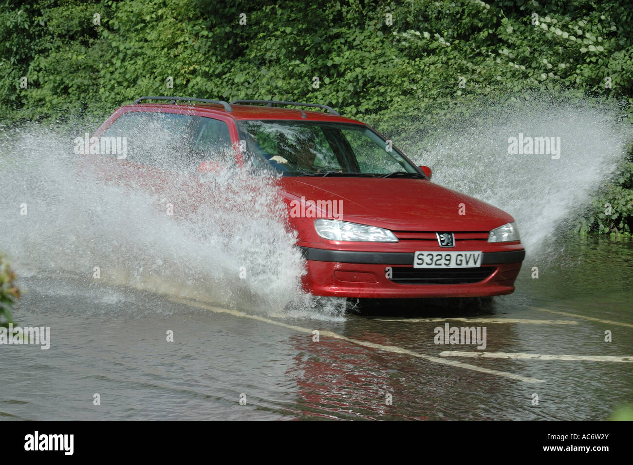 A motor car on a road driving through flood water Stock Photo - Alamy