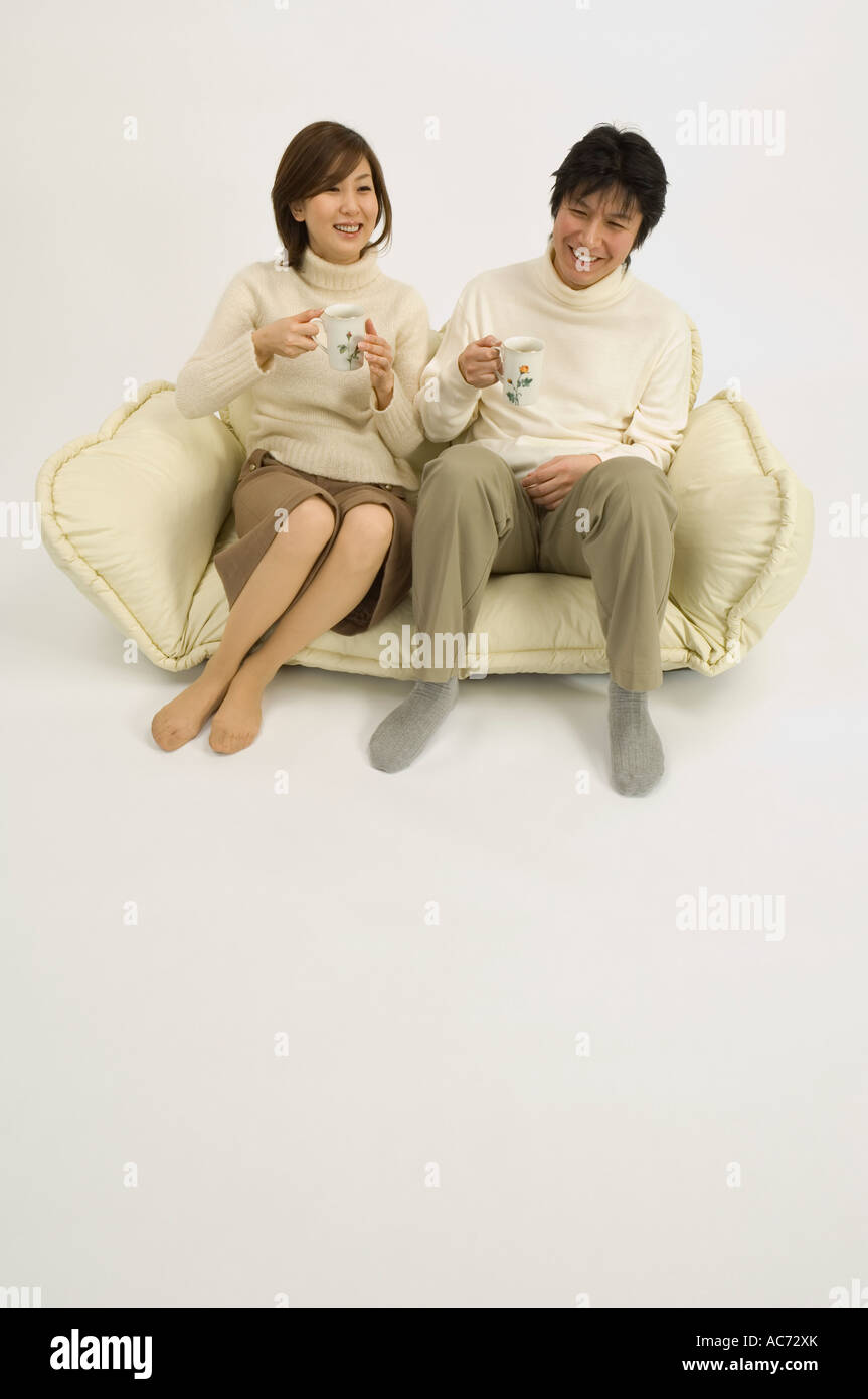 Couple drinking coffee on sofa Stock Photo - Alamy