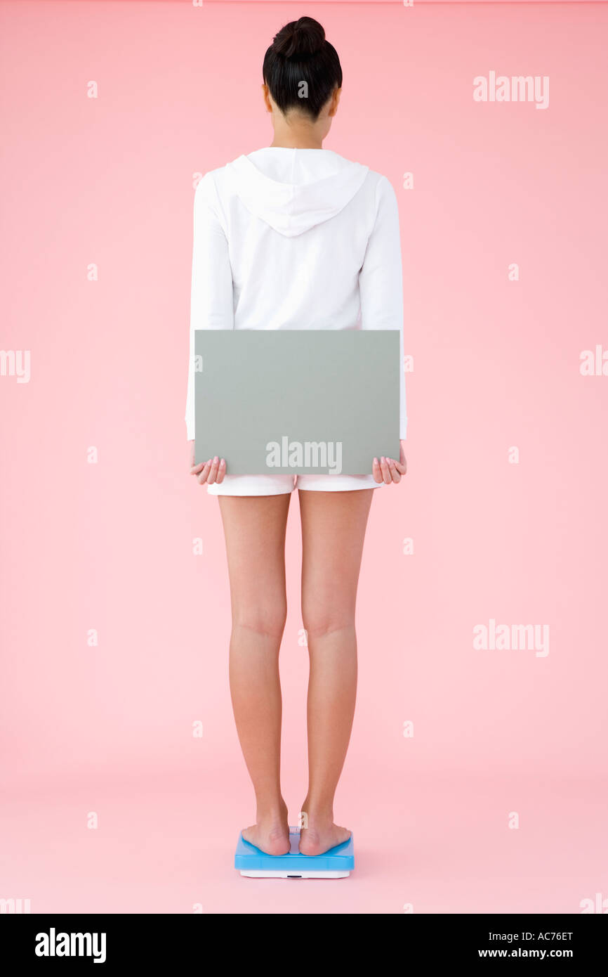 Woman standing on bathroom scale holding blank placard Stock Photo - Alamy