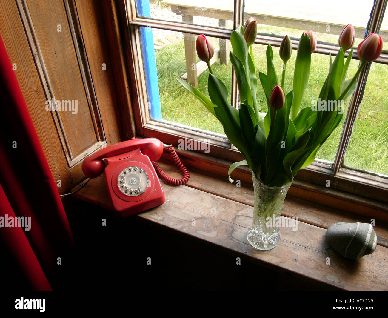 An old red dial up rotary telephone on a window ledge of a house UK ...