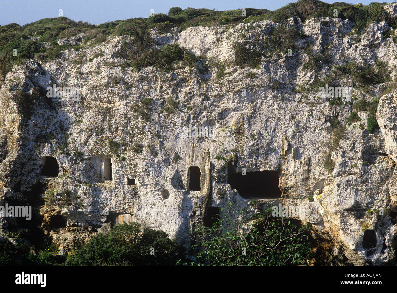 caves cut out of the limestone cliffs above a long inlet at Cala de ...