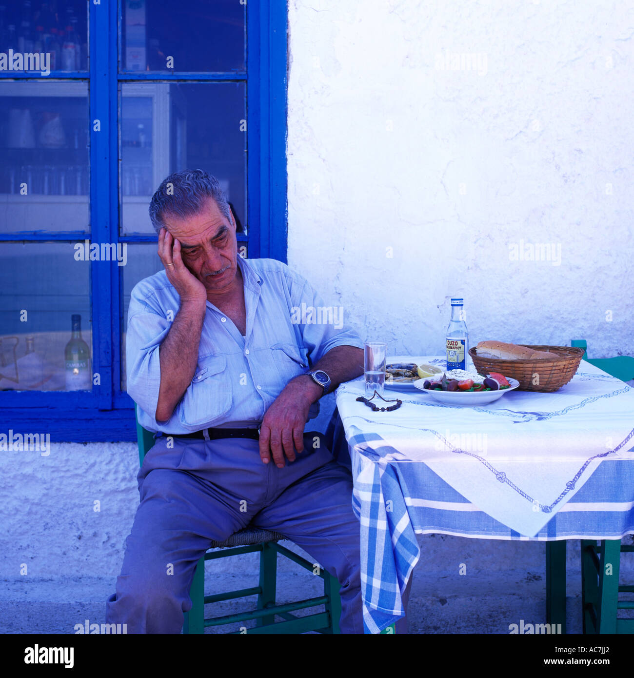 WORRIED LOOKING GREEK MAN SITTING ALONE AT TAVERNA TABLE POSED Stock ...