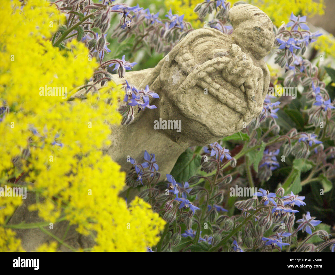 beautiful stone female statue surrounded by blue and yellow spring ...