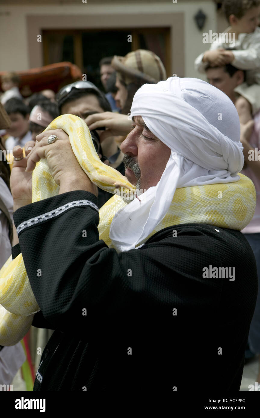 Man in white turban kissing large yellow python during medieval market ...