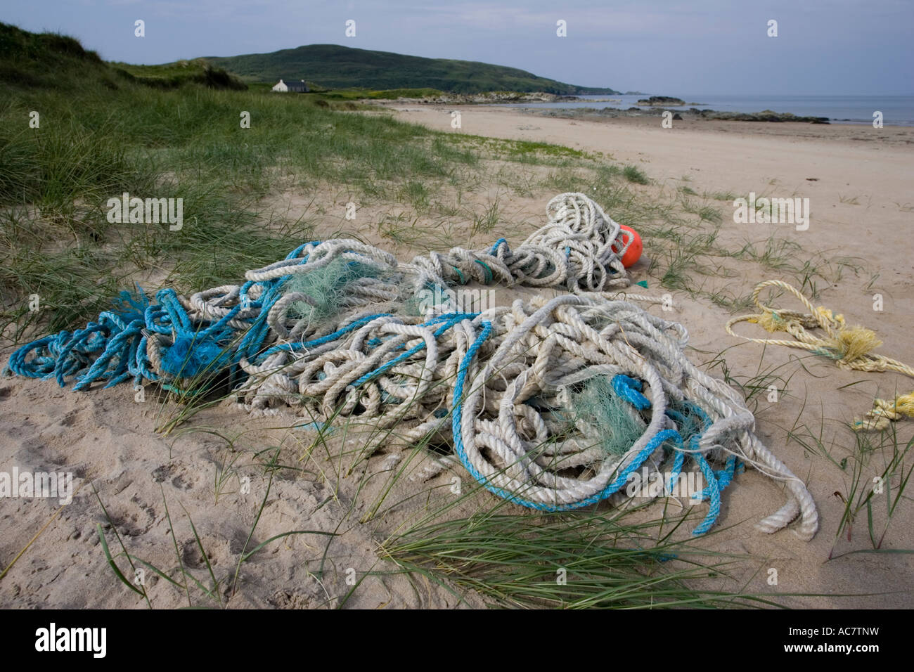 Discarded rope and fishing net washed up on sandy beach Kintra Isle of ...