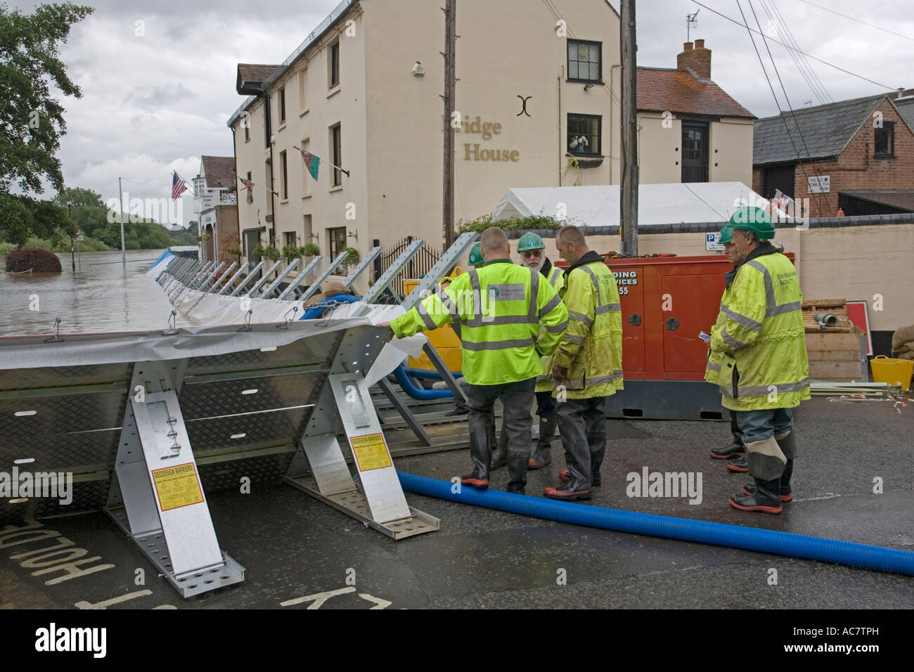 Environment Agency Officials Alongside Flood Barriers Alongside River