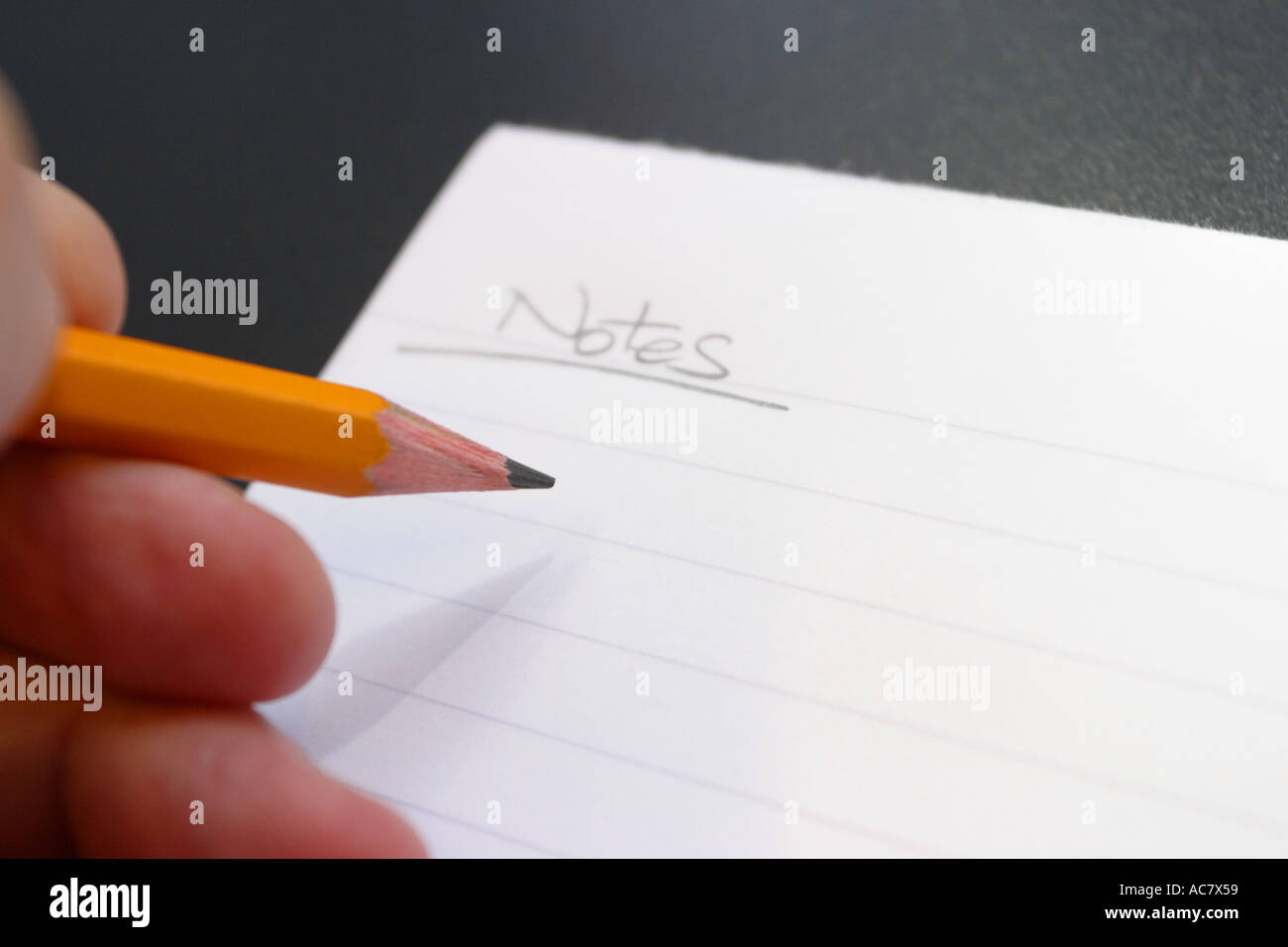Pencil in hand with notepad making notes Stock Photo - Alamy