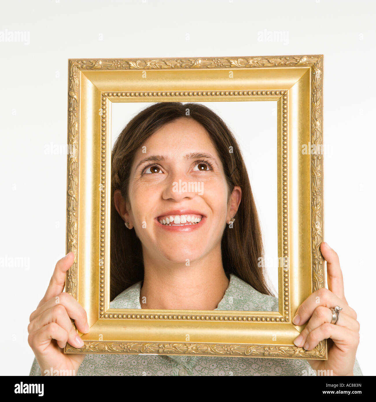 Woman holding frame in front of face smiling Stock Photo - Alamy