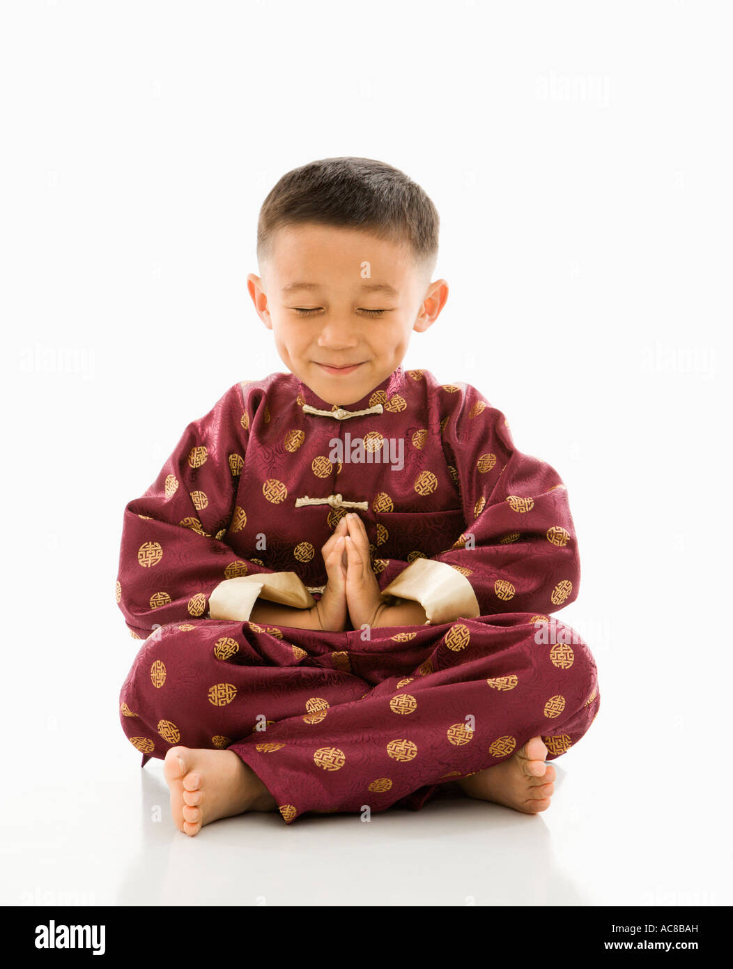 Asian boy sitting meditating against white background in traditional ...
