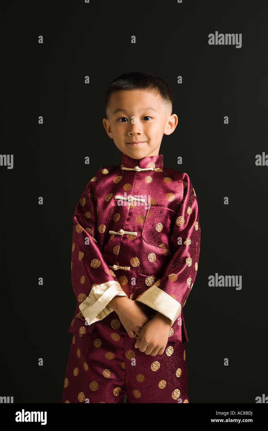Asian boy in traditional attire standing against black background Stock ...