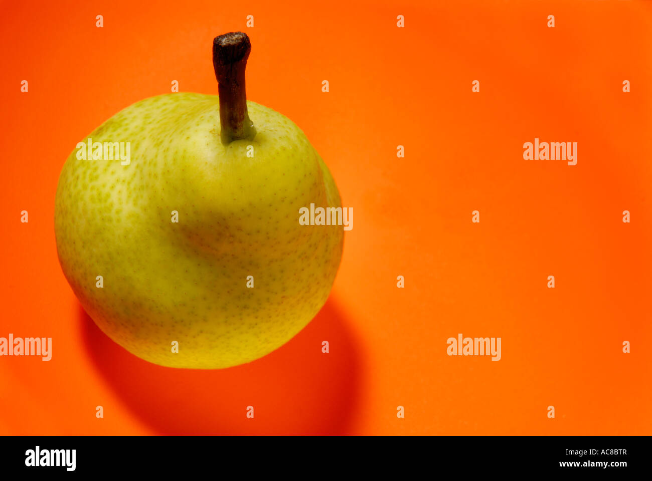 Green Pear on Orange Background Stock Photo - Alamy