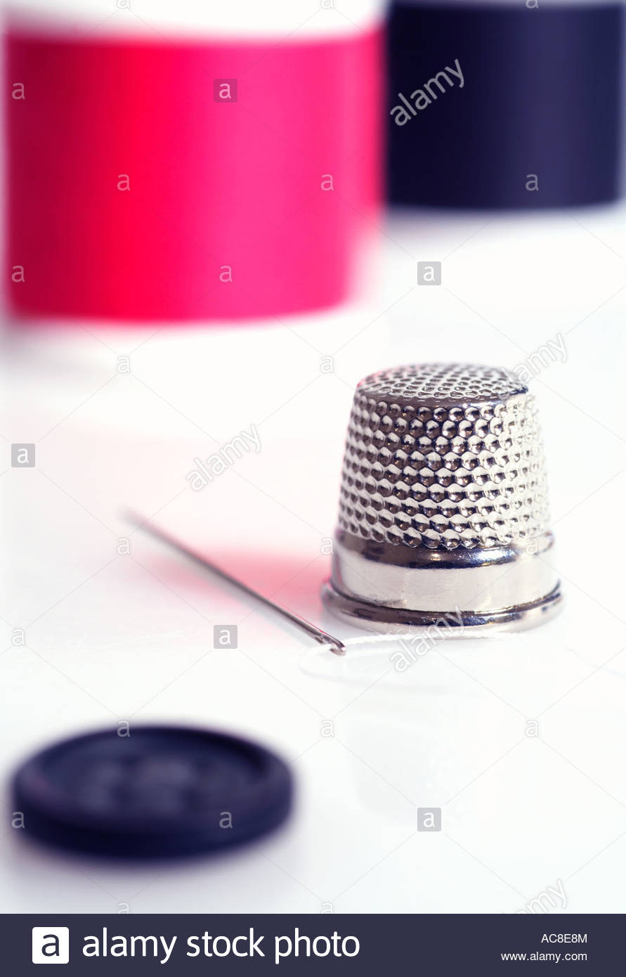 Thimble button cotton reel needle and thread Stock Photo - Alamy