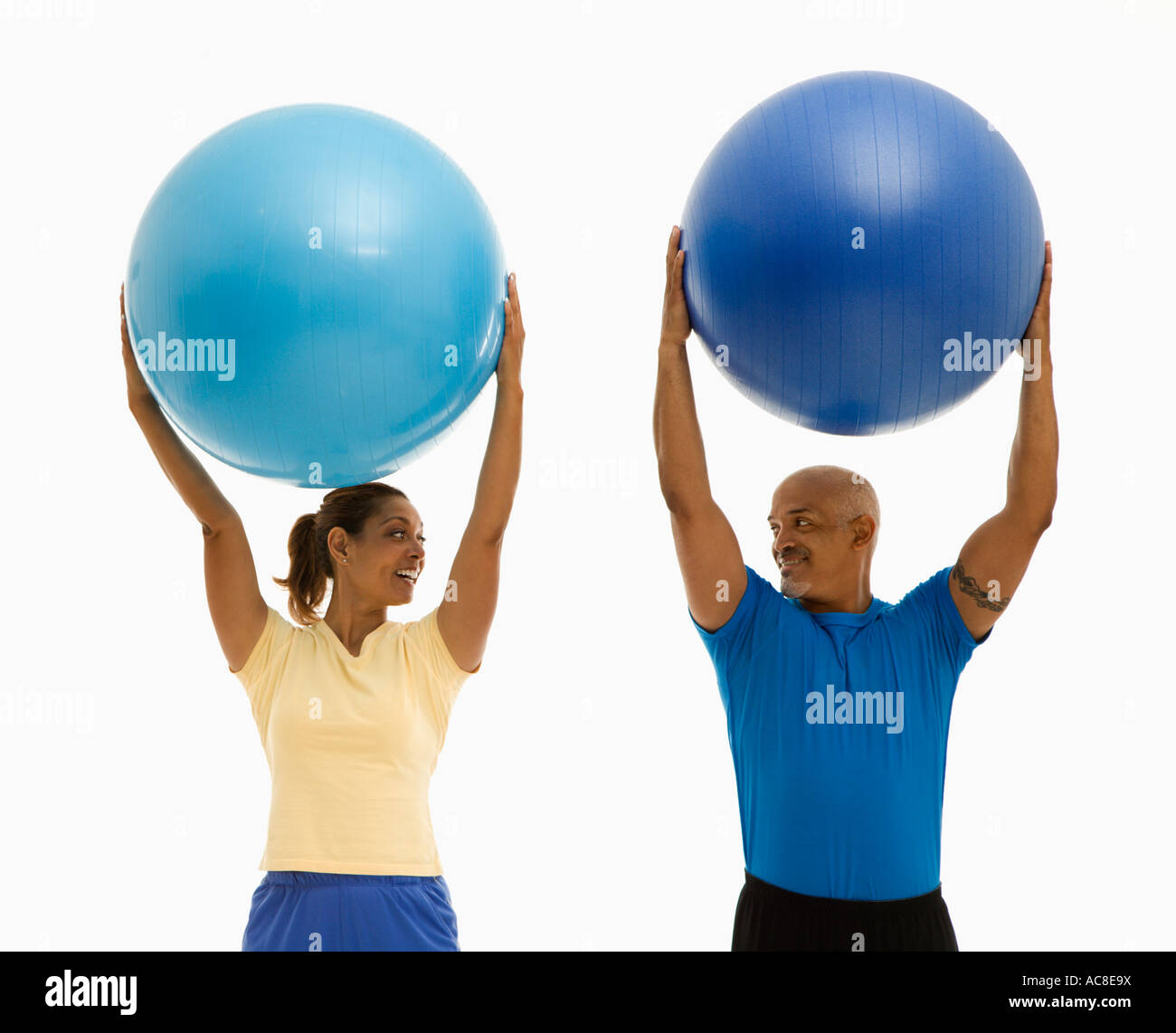 Happy smiling mid adult multiethnic man and woman holding blue exercise ...