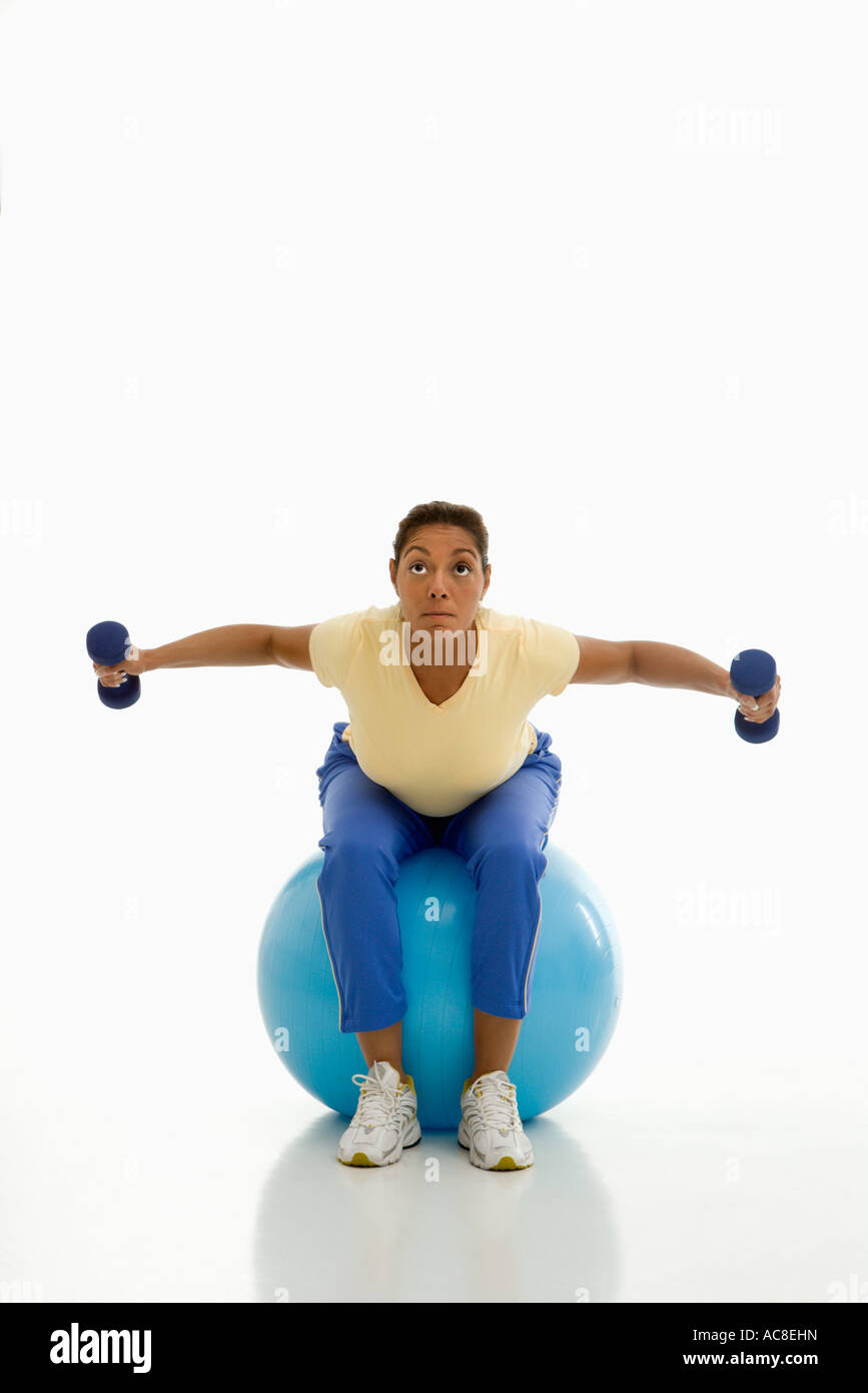 Mid adult multiethnic woman balancing on blue exercise ball with ...