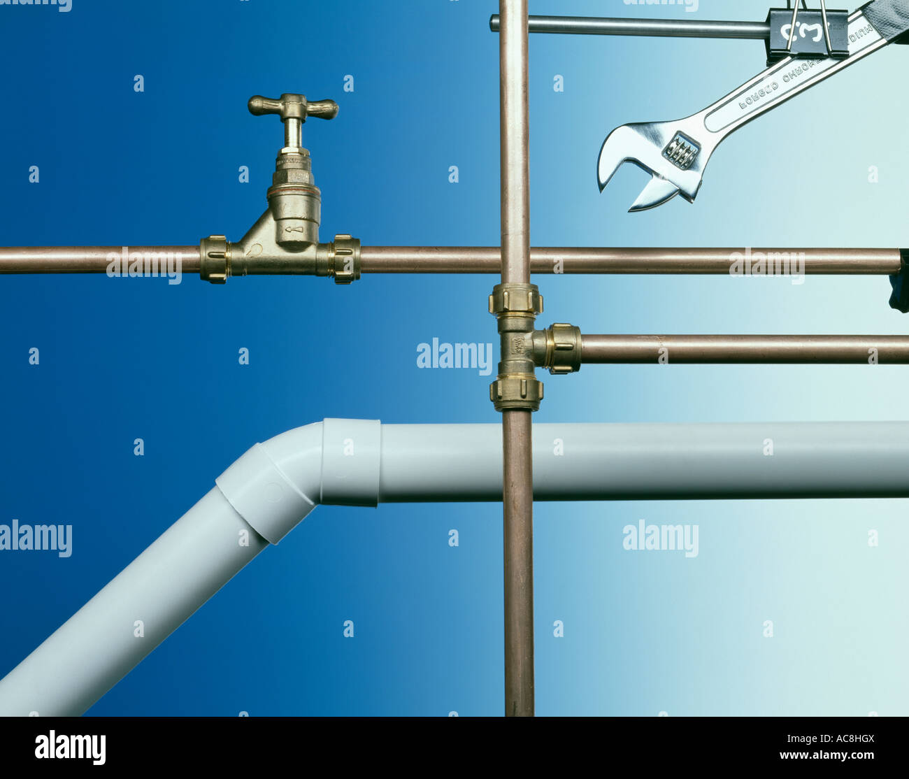 Close up of copper tap and plumbing pipes with wrench and white plastic ...