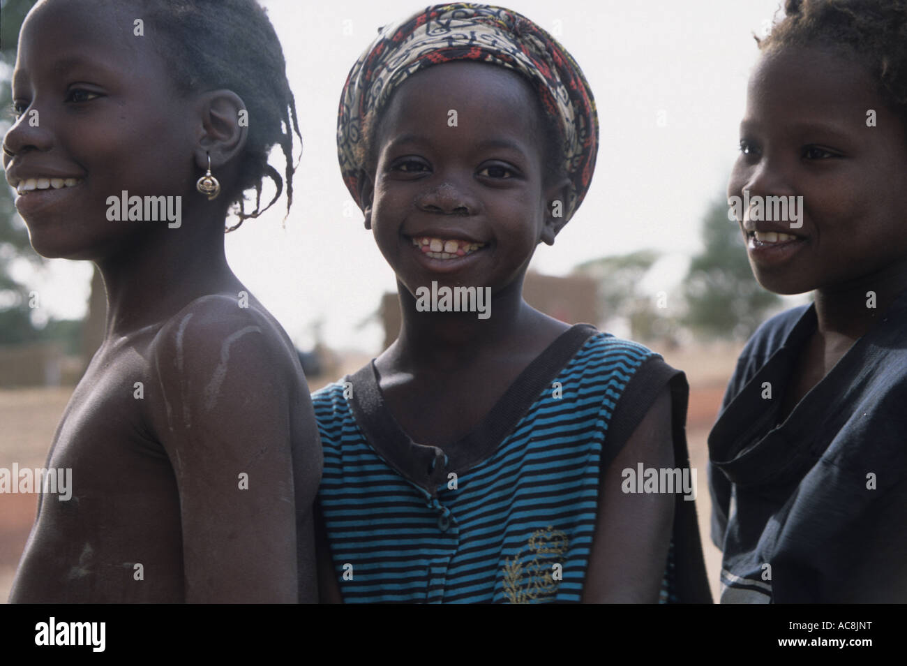 Three young girls sitting by a well in their village in South Mali ...
