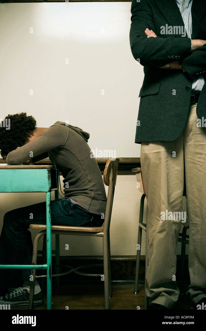 Teacher standing next to a student sleeping at her desk Stock Photo - Alamy